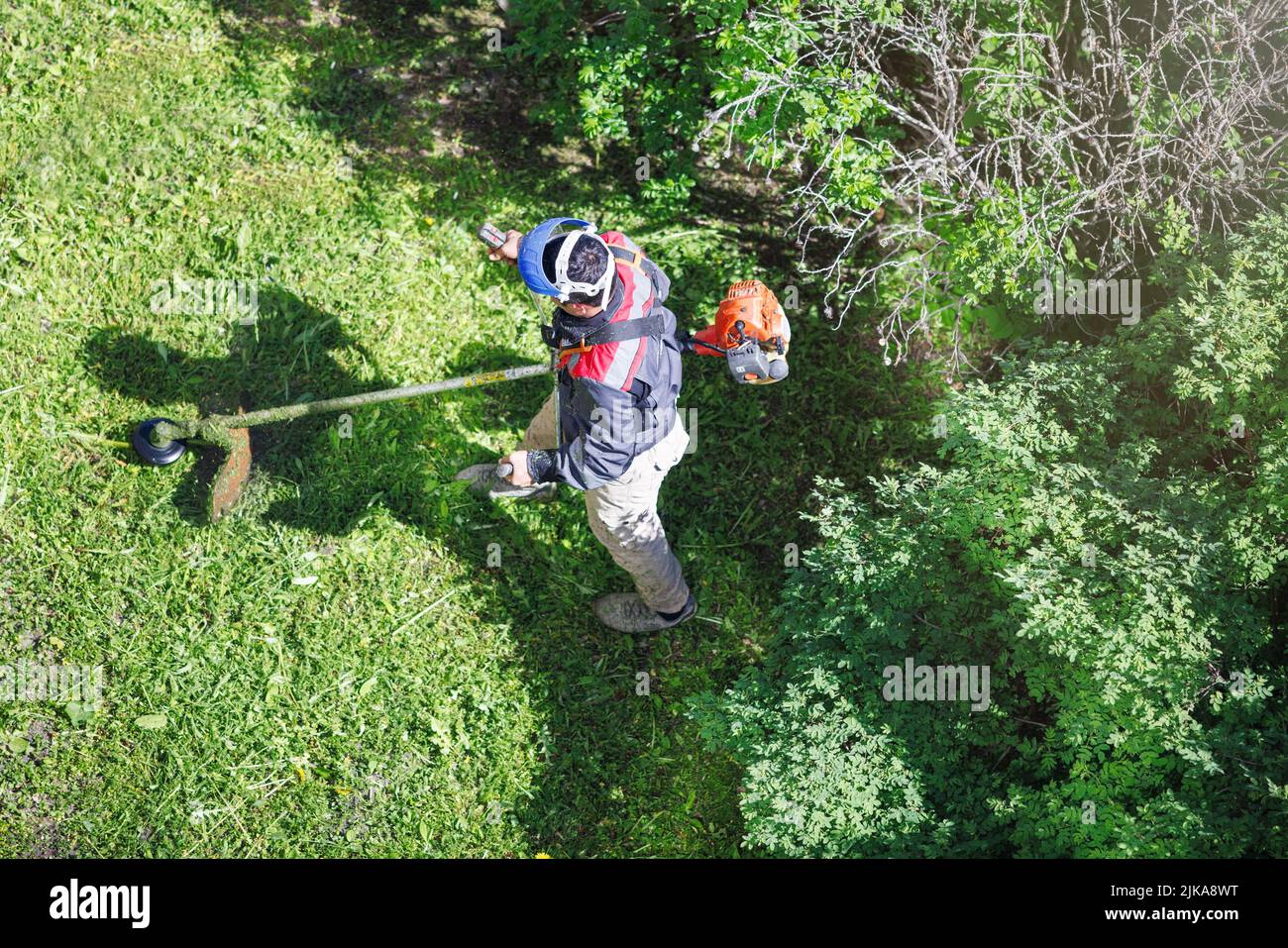 A man mows the grass with a lawn mower. Landscaping works on ...
