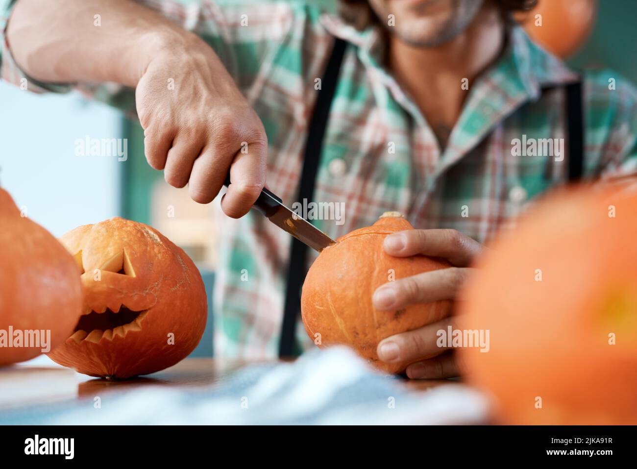 Carving the perfect pumpkin is a skill. a young man carving a pumpkin ...