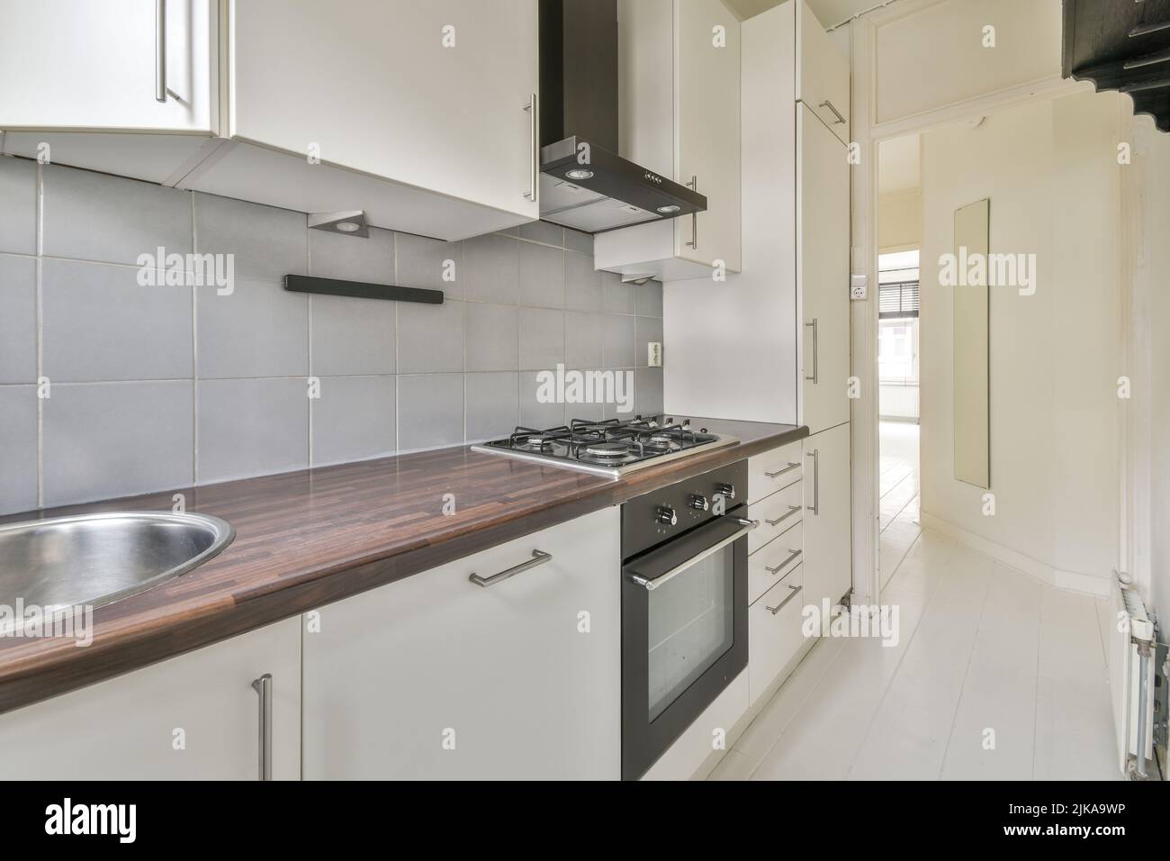 Interior of empty white kitchen with corridor and wooden parquet floor ...