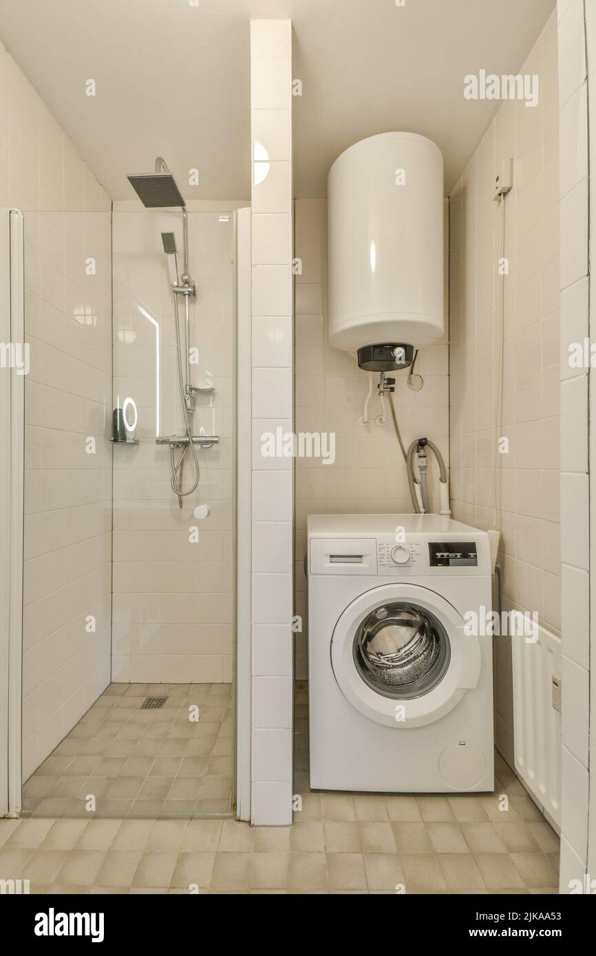 Shower faucets attached to tiled wall near glass partition and washing ...
