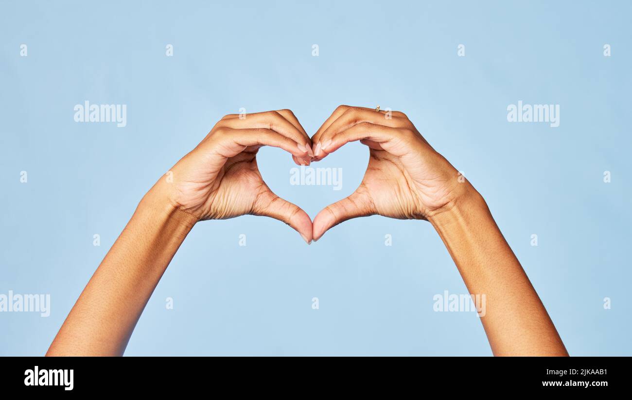 Spread love and kindness. a hand making a gesture shot against a studio ...