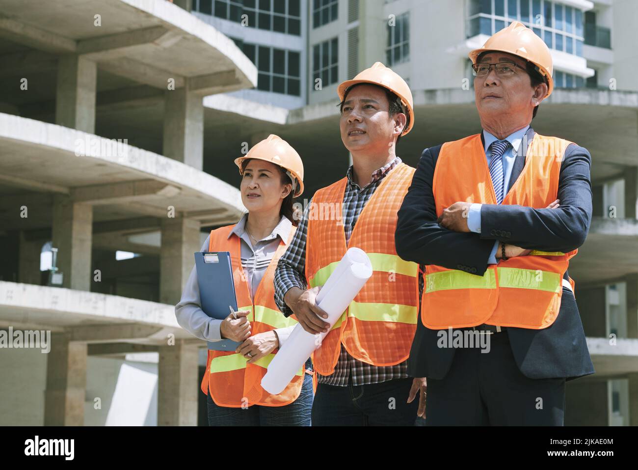 Team of Asian engineers proudly looking at the buildings under ...