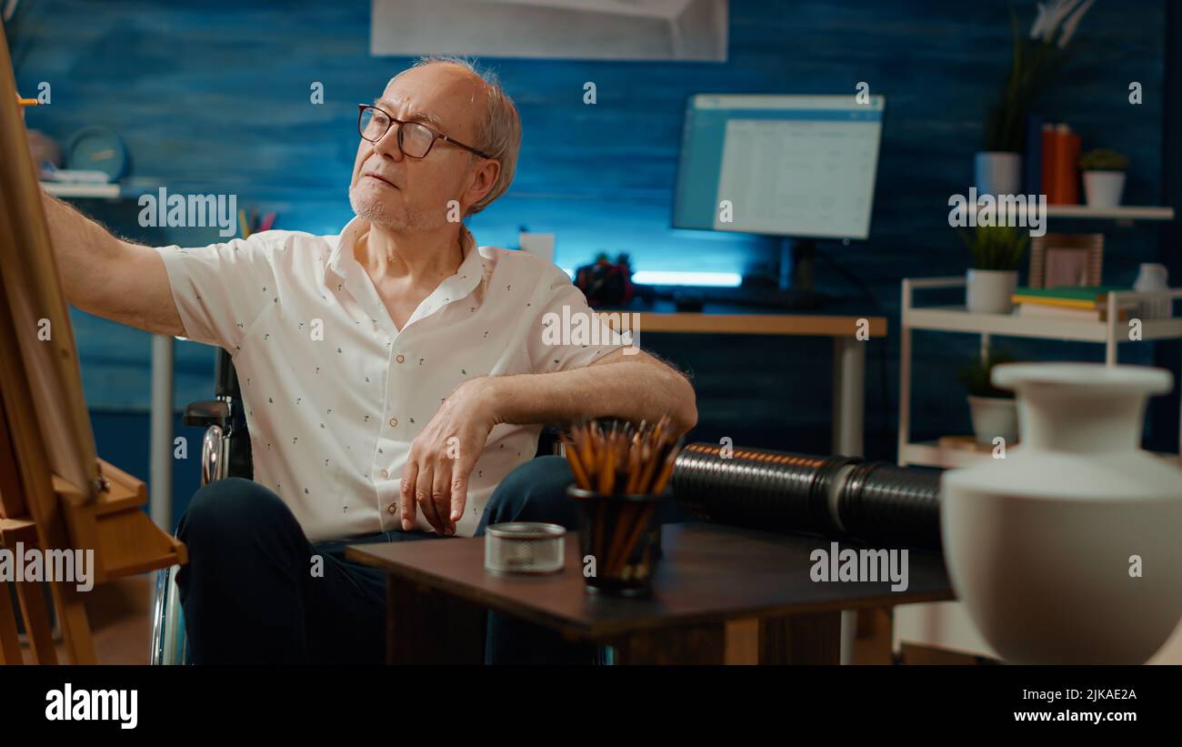 Senior artist with physical impairment drawing vase design on white ...