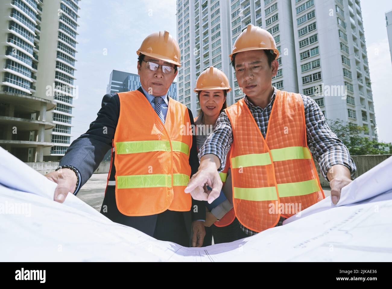 Team of Vietnamese engineers analyzing construction blueprint Stock Photo - Alamy