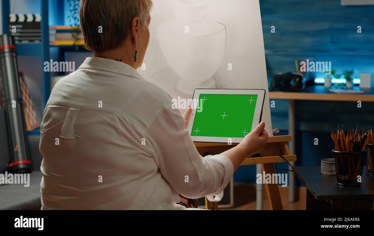 Senior woman looking at greenscreen on digital tablet, drawing ...