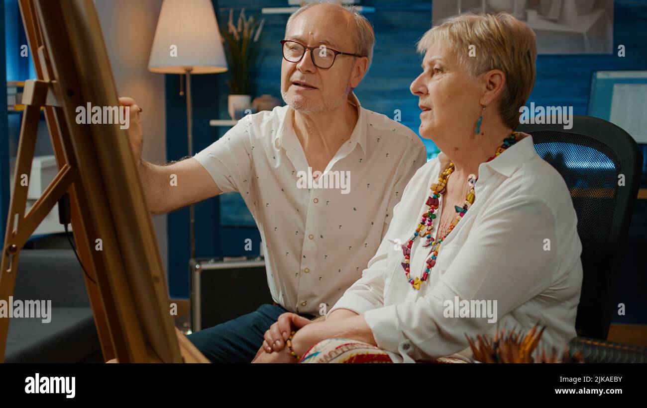 Senior people doing teamwork drawing to create sketch model on canvas ...