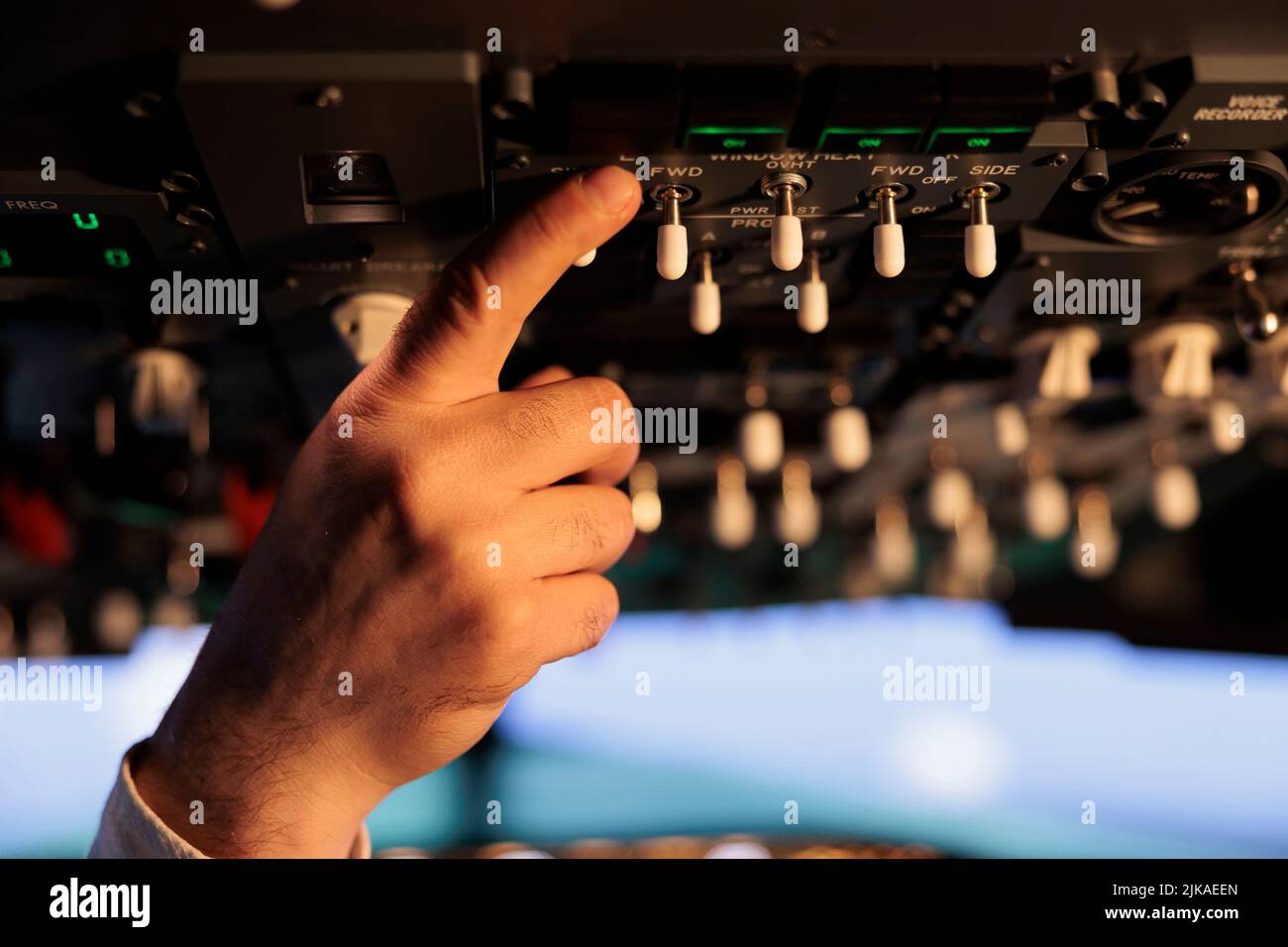 Male captain using control panel in cockpit to fly airborne aircraft ...