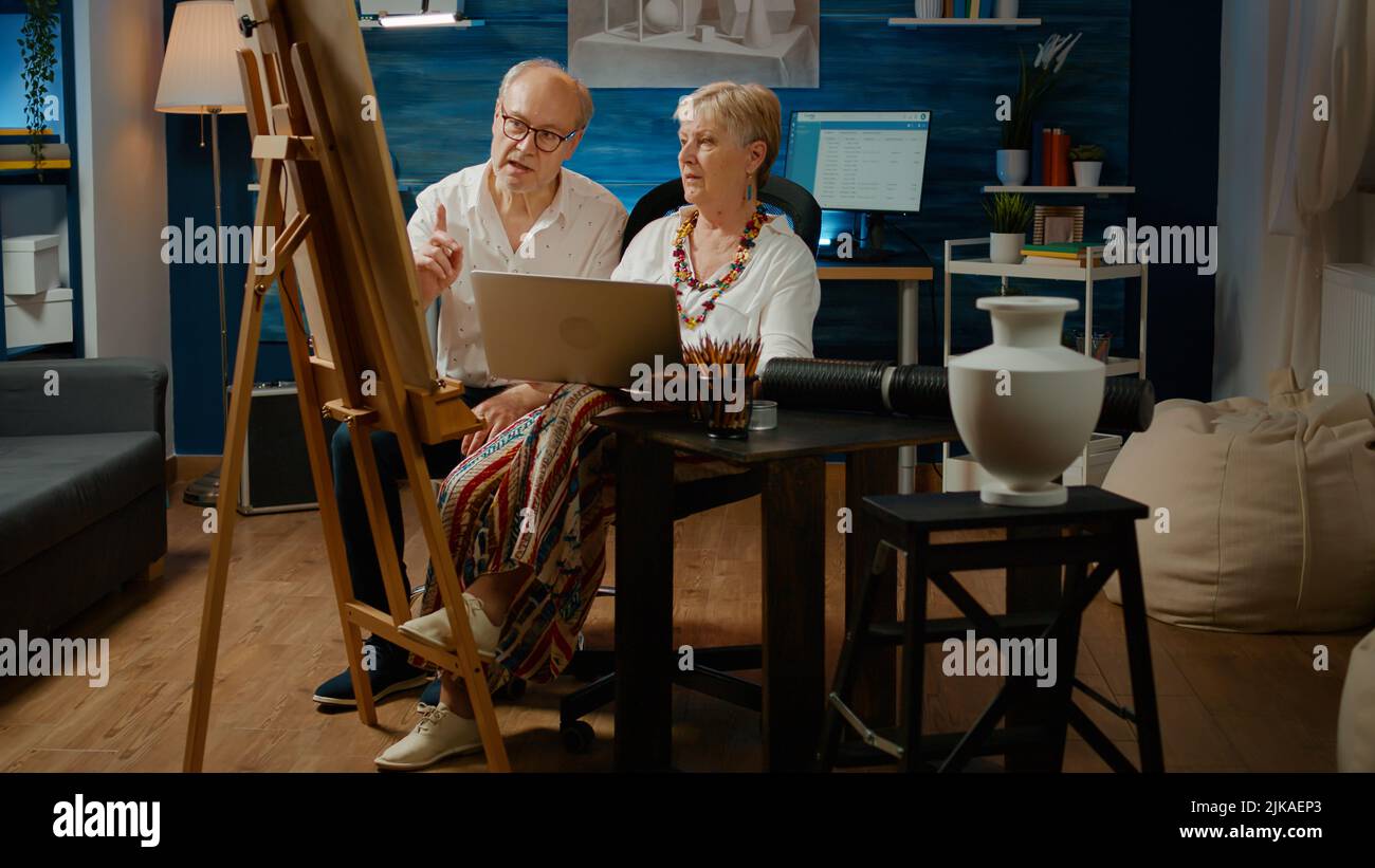 Team of senior artists looking at artistic inspiration on laptop, drawing masterpiece sketch ...