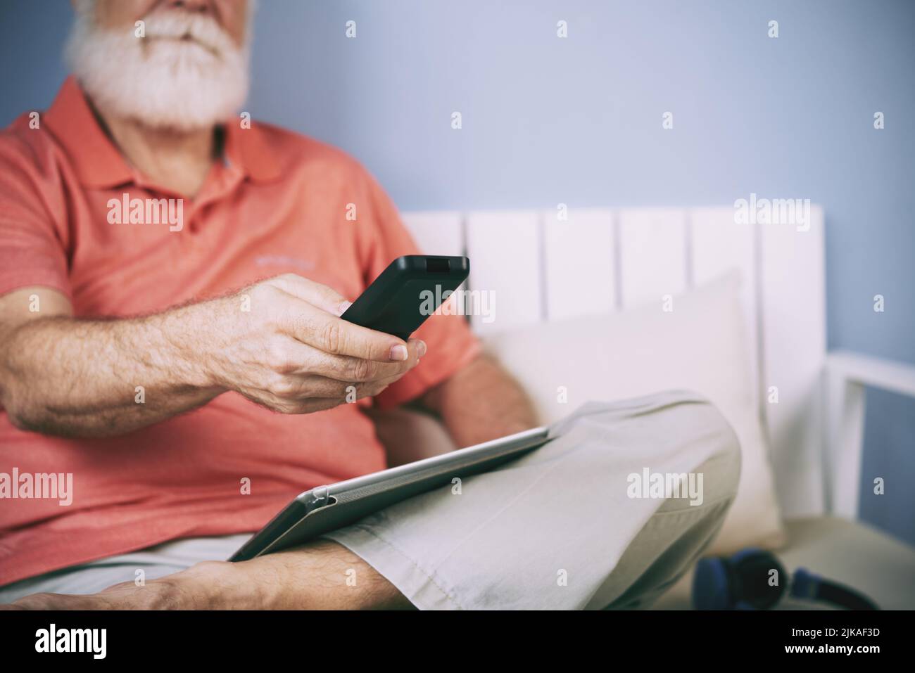 Senior man holding remote control in his hand to switch channels ...