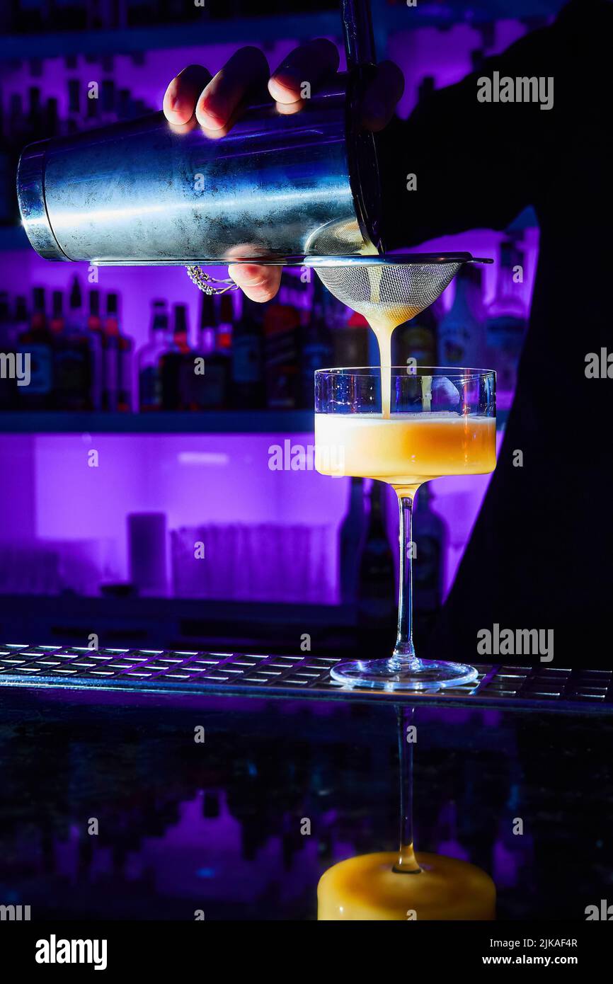 Bartender prepares Is Love alcohol cocktail on bar counter using shaker ...