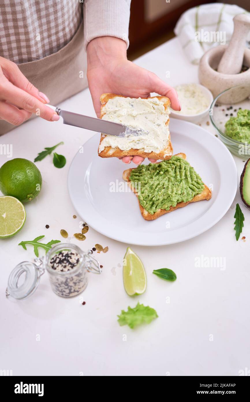 Toasts preparation - woman smearing cream cheese on a toasted bread ...