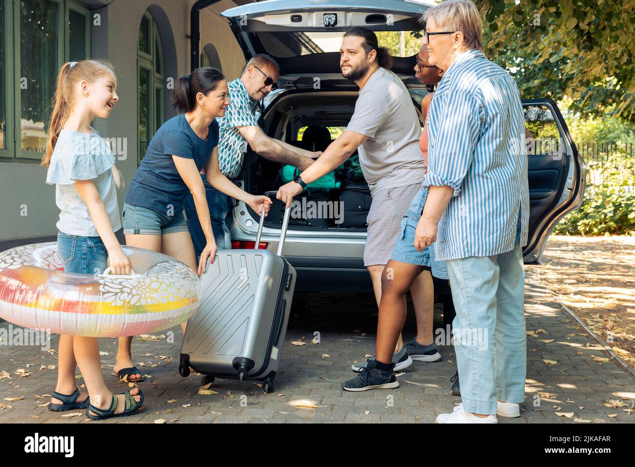 Diverse people loading baggage in vehicle trunk, travelling on holiday ...