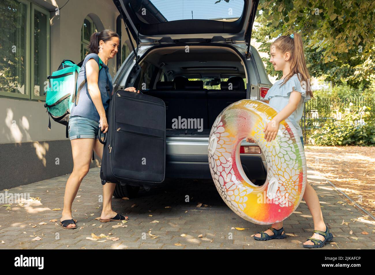 Mother and little girl leaving on vacation, loading luggage, bags and ...