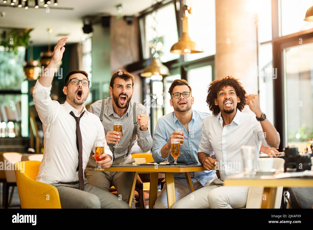 Friends cheering. Four happy soccer fans drinking beer at the pub Stock ...