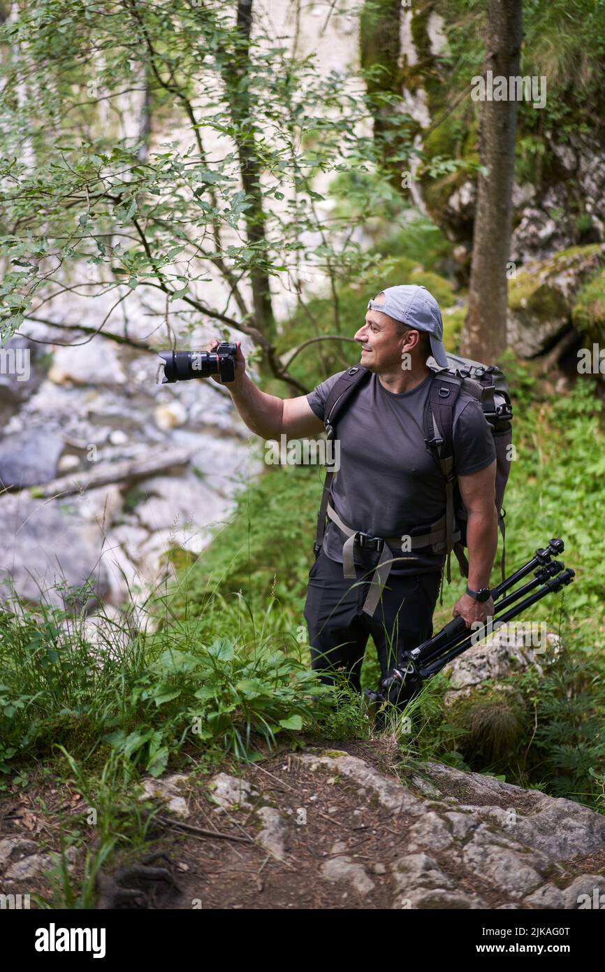 Nature photographer with camera hiking with his backpack on a trail in ...
