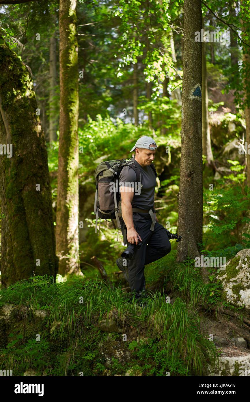 Nature photographer with camera hiking with his backpack on a trail in ...