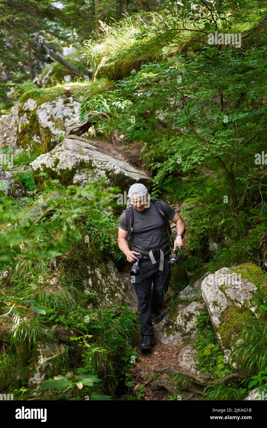 Nature photographer with camera hiking with his backpack on a trail in ...