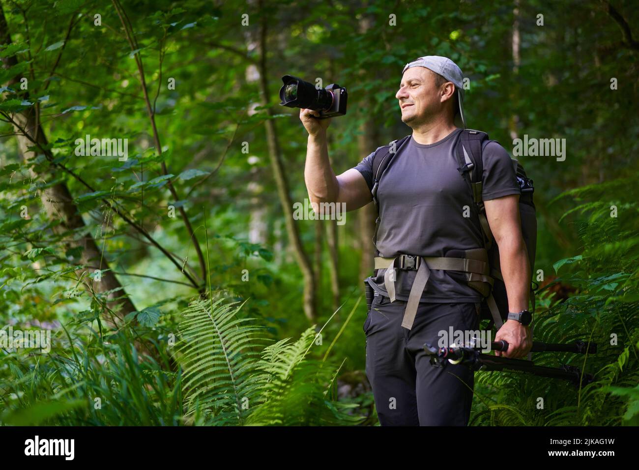 Nature photographer with camera hiking with his backpack on a trail in ...