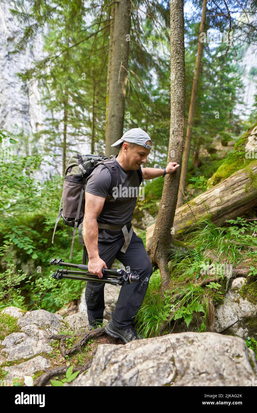 Nature photographer with camera hiking with his backpack on a trail in ...