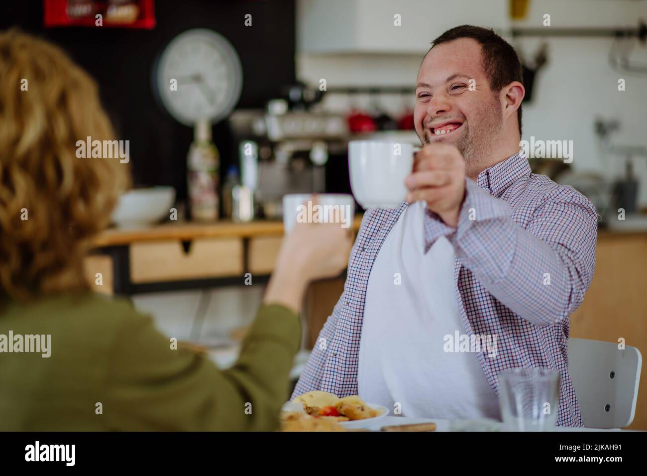 Portrait of happy young man with Down syndrome with his mother at home ...