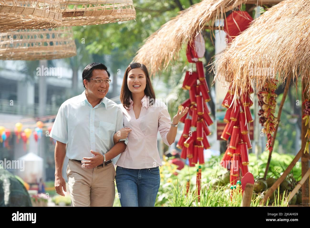 Happy Vietnamese young woman and her dad talking when walking in the ...