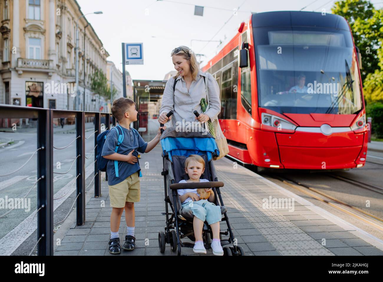 Young mother commuter with little kids on the way to school, walking on ...