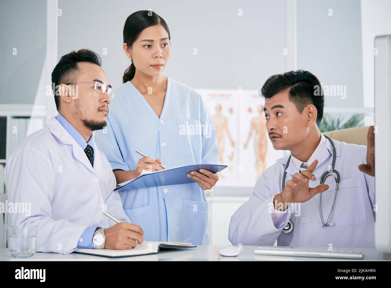 Doctor showing information on computer screen to interns Stock Photo ...
