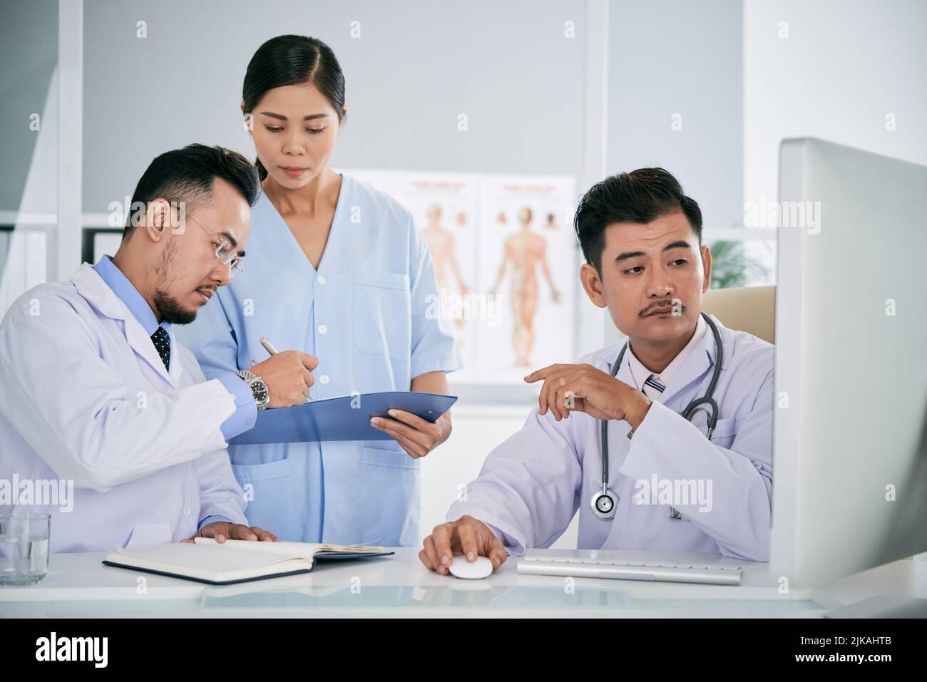 Doctor watching something on computer screen when his coworker signing ...