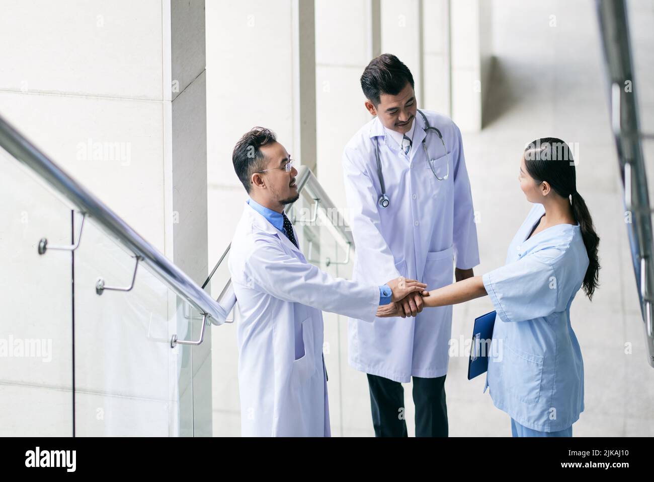 Team of Asian medical workers stacking hands to support each other ...