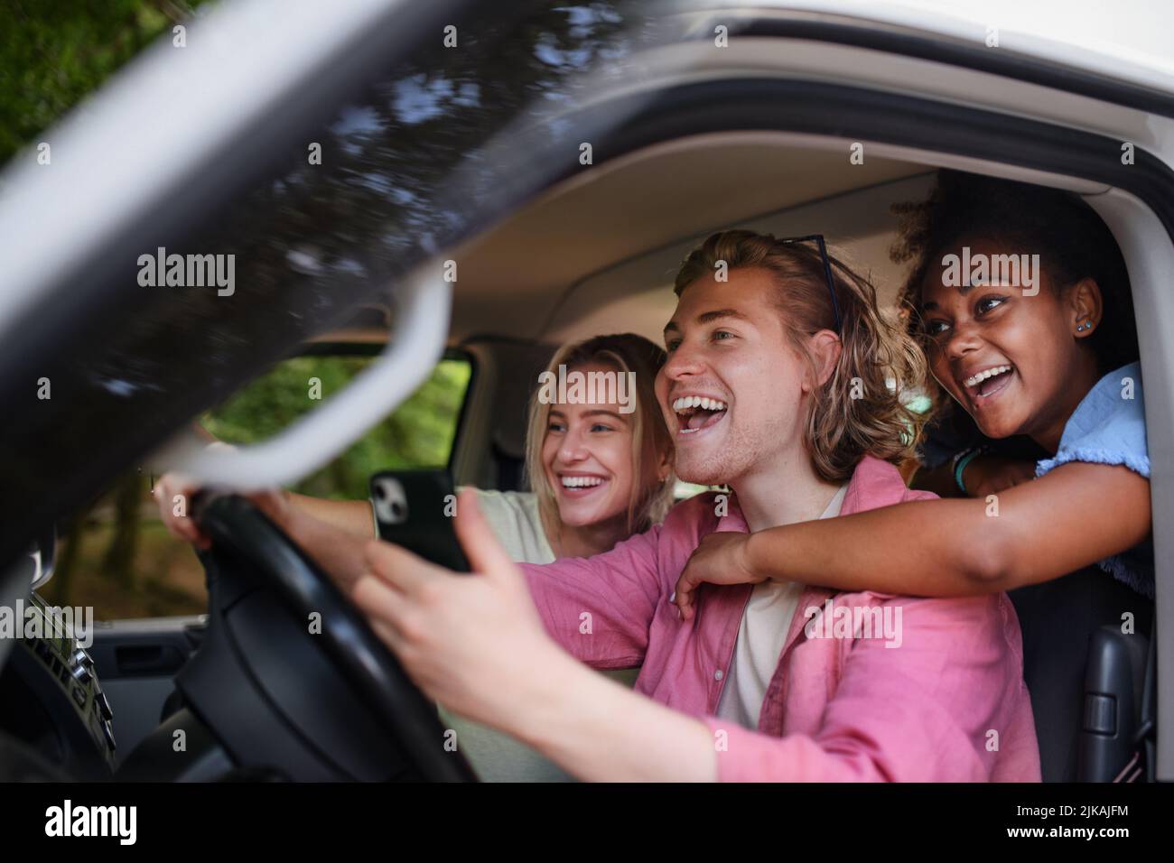 Multiracial young friends travelling together by car, having fun ...
