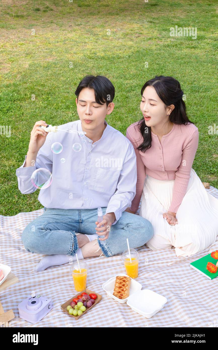 Asian Korean couple enjoying spring picnic playing with bubbles Stock ...