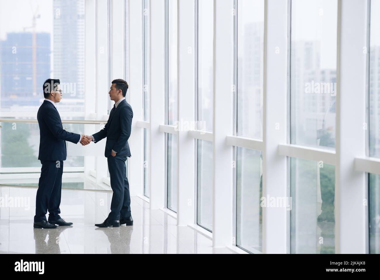 Asian business partners shaking hands after talk Stock Photo - Alamy