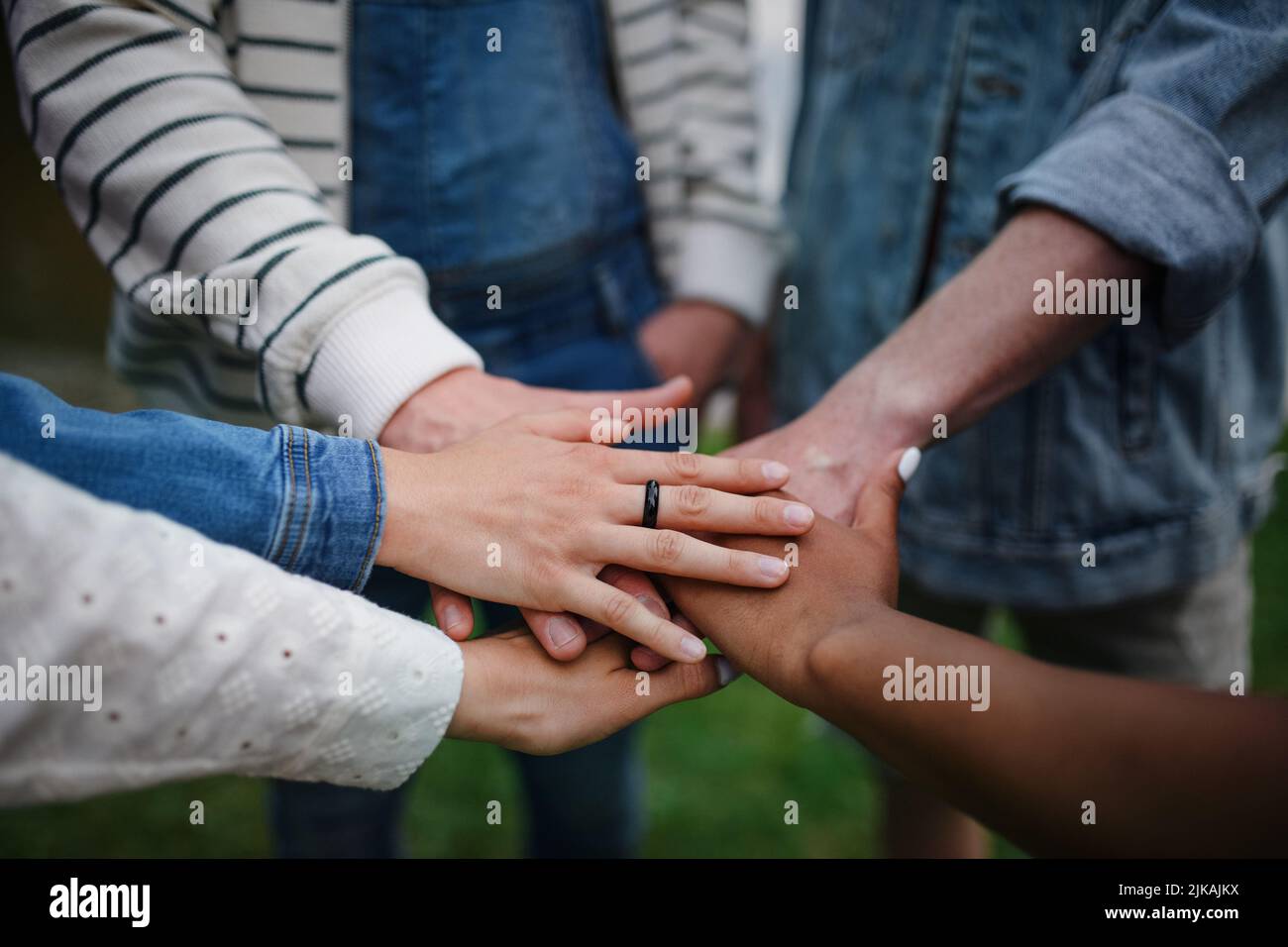 Close-up of diverse group of friends stacking their hands together in ...