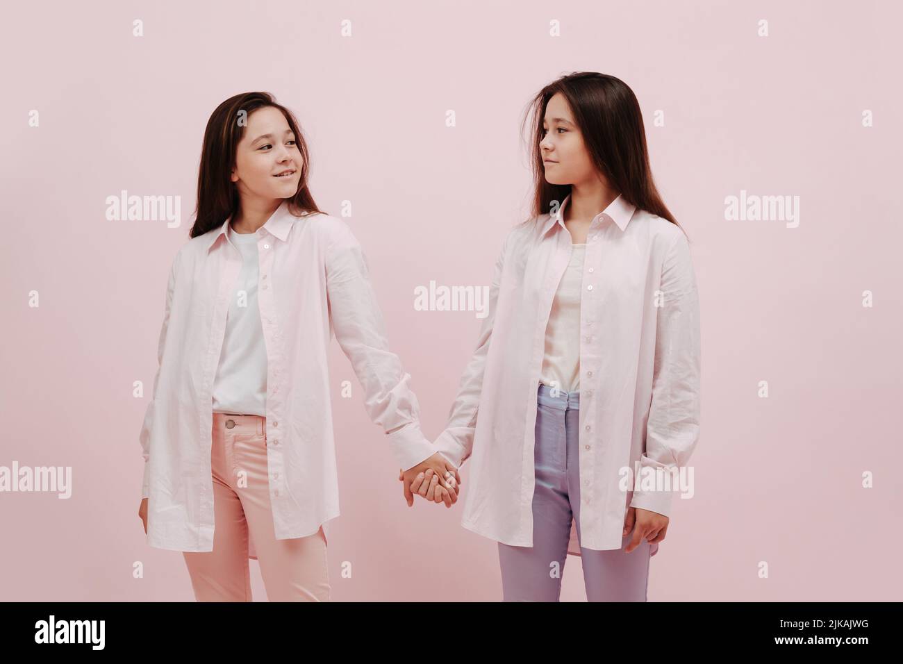 Affectionate twins holding hands, looking at each other Stock Photo - Alamy