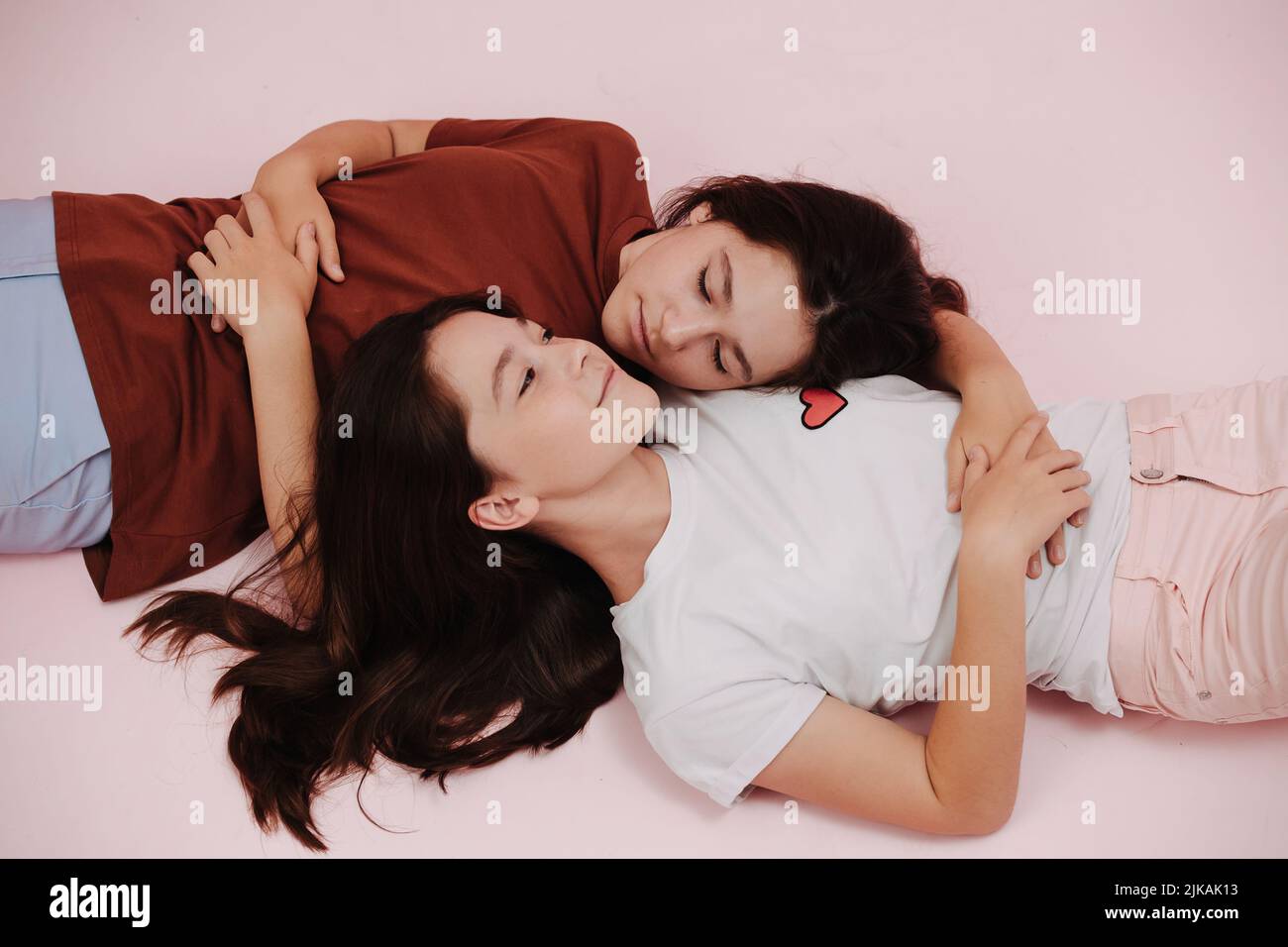 Reaxing twin girls lying on the floor in opposite, resting heads on one ...