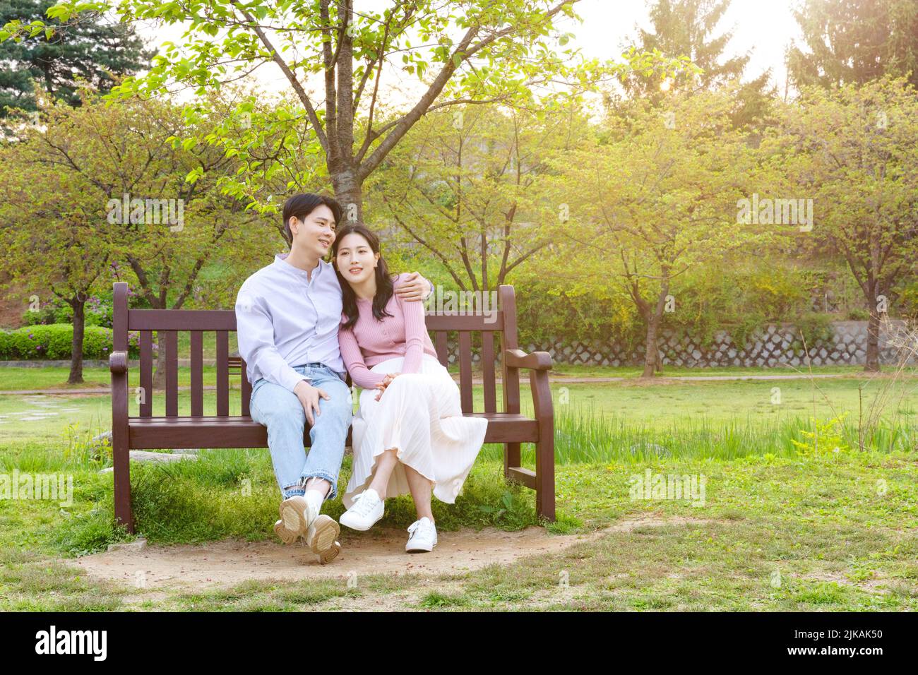 Korean Asian couple enjoying spring date sitting on the bench Stock ...