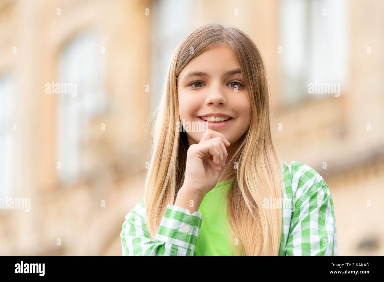 Portrait of happy teen girl smiling with chin on hand blurry outdoors ...