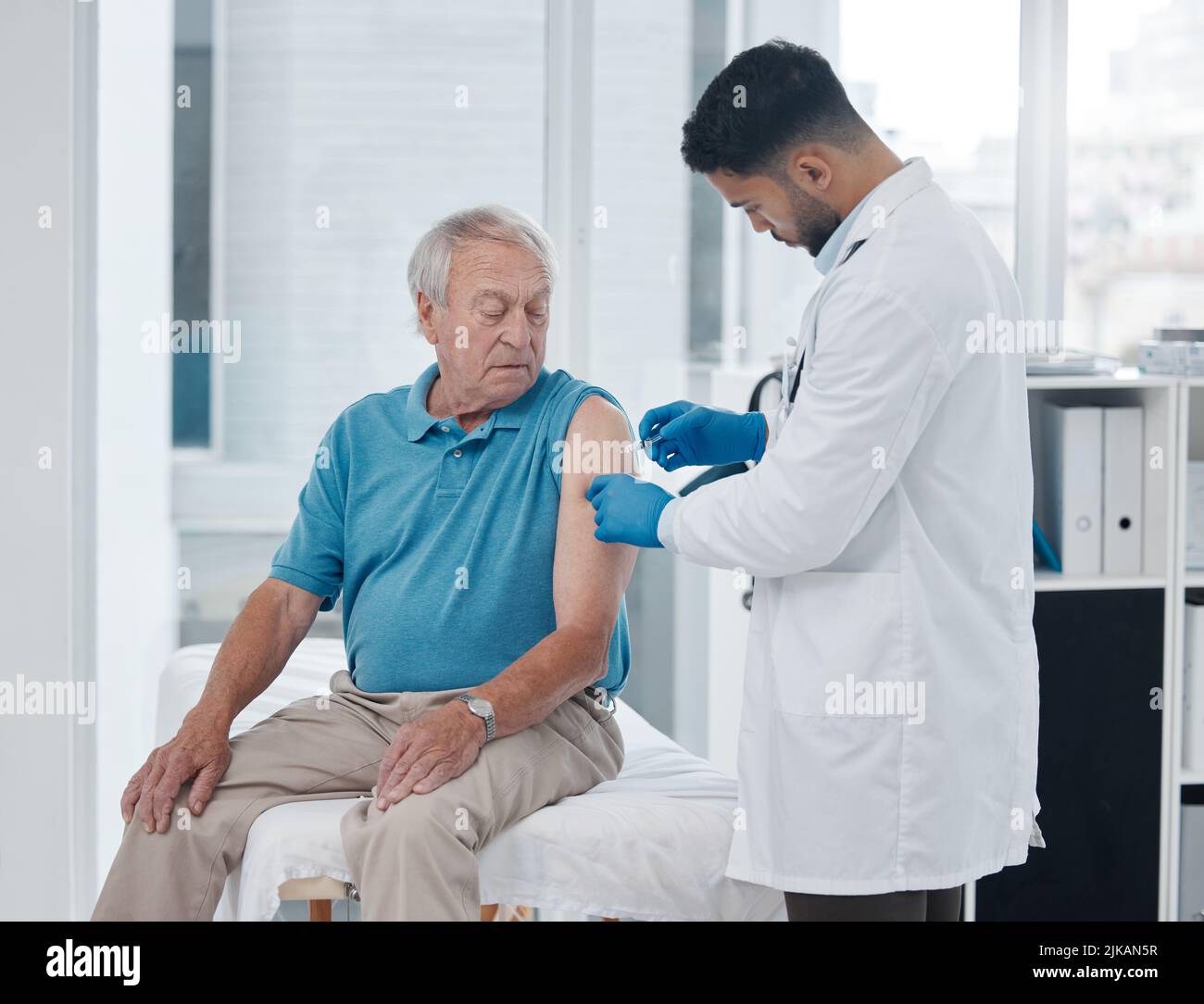 It might sting a little. a handsome young male doctor administering the ...