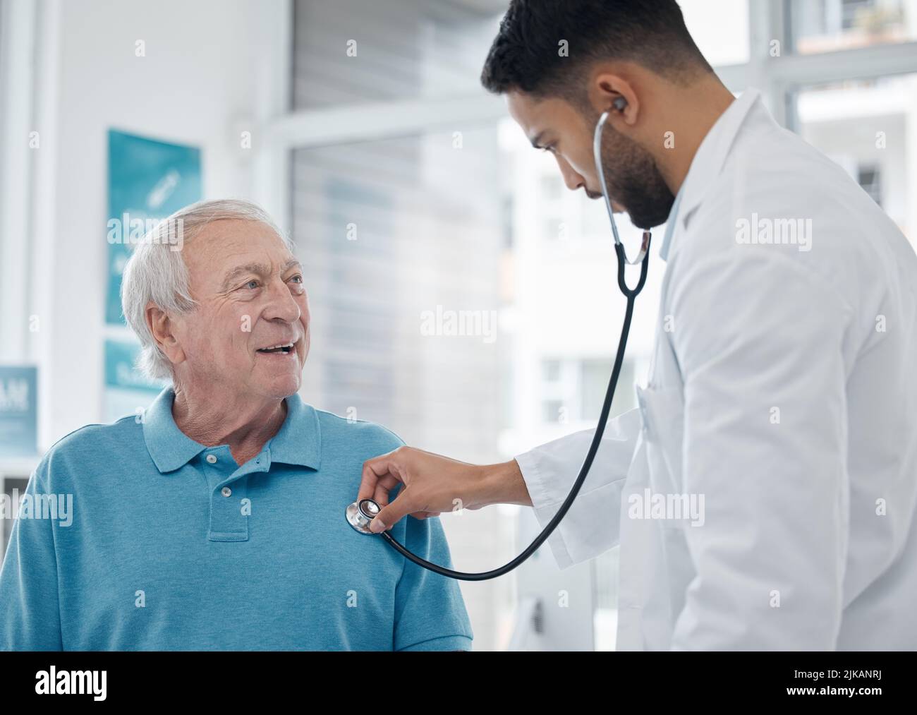 Just breathe in and out for me. a young doctor examining a mature man ...