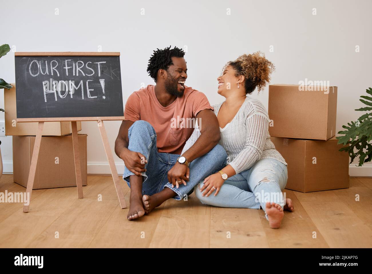 People make a house into a home. Portrait of a young couple sitting on ...