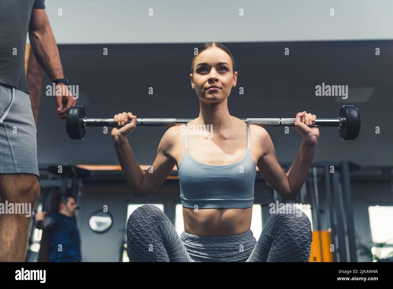 Fit girl doing squats with weights in gym and male trainer watching her. High quality photo ...
