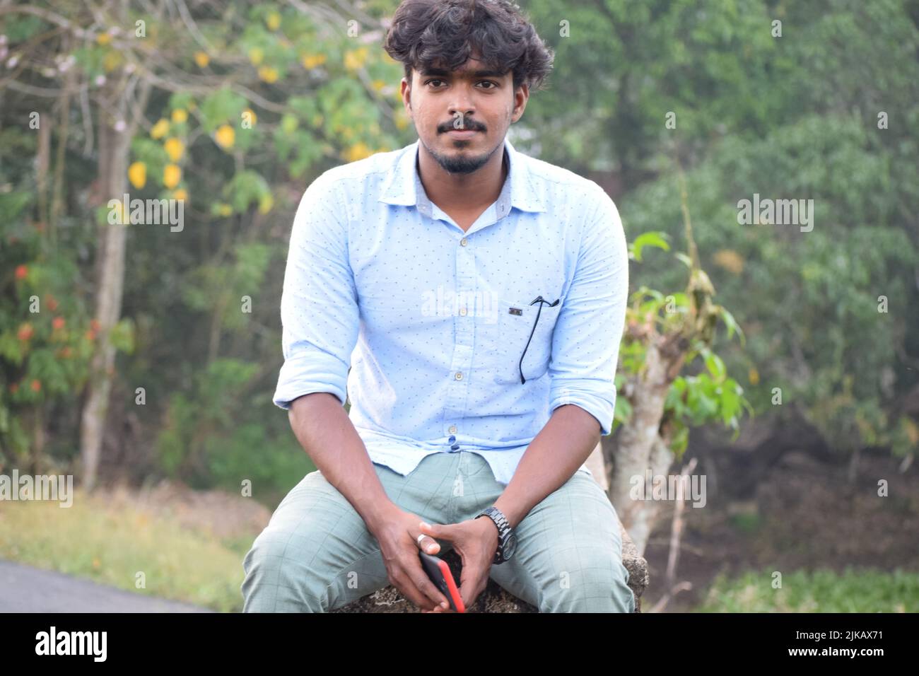indian boy sitting on a cement bench and relaxing Stock Photo - Alamy