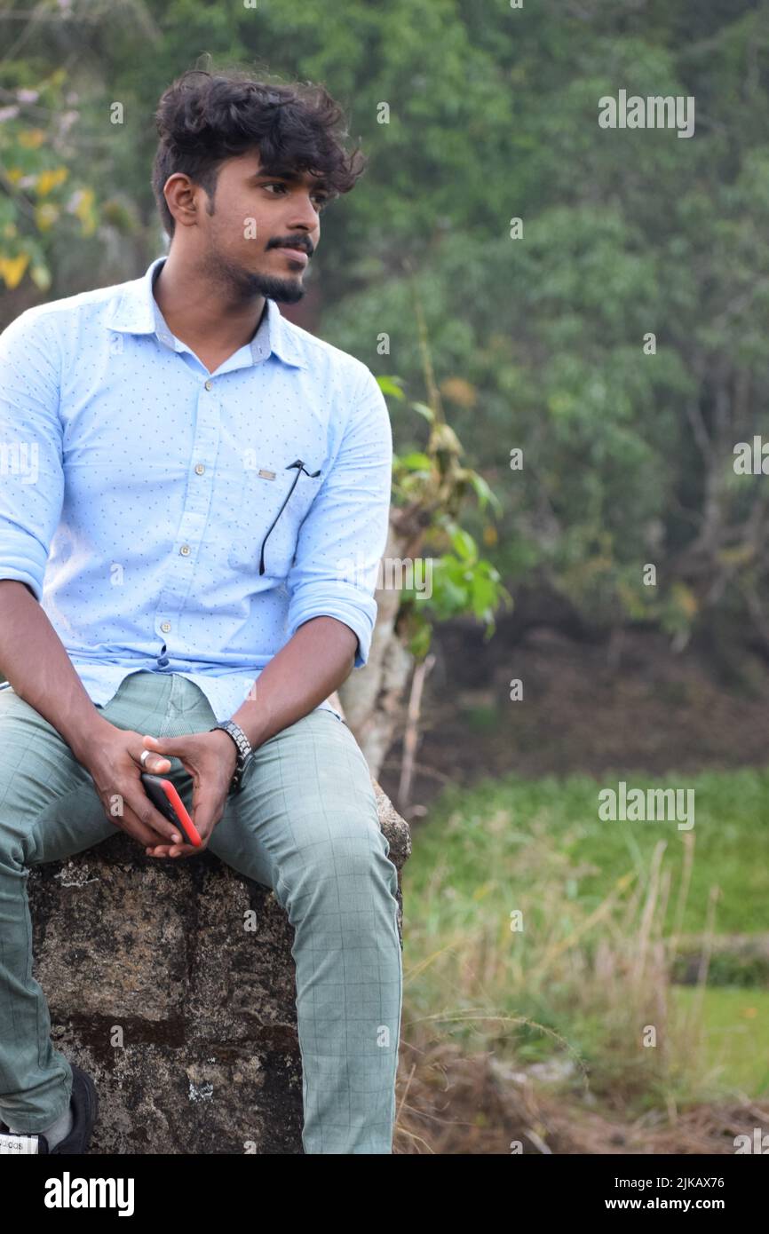 indian boy sitting on a cement bench and relaxing Stock Photo - Alamy