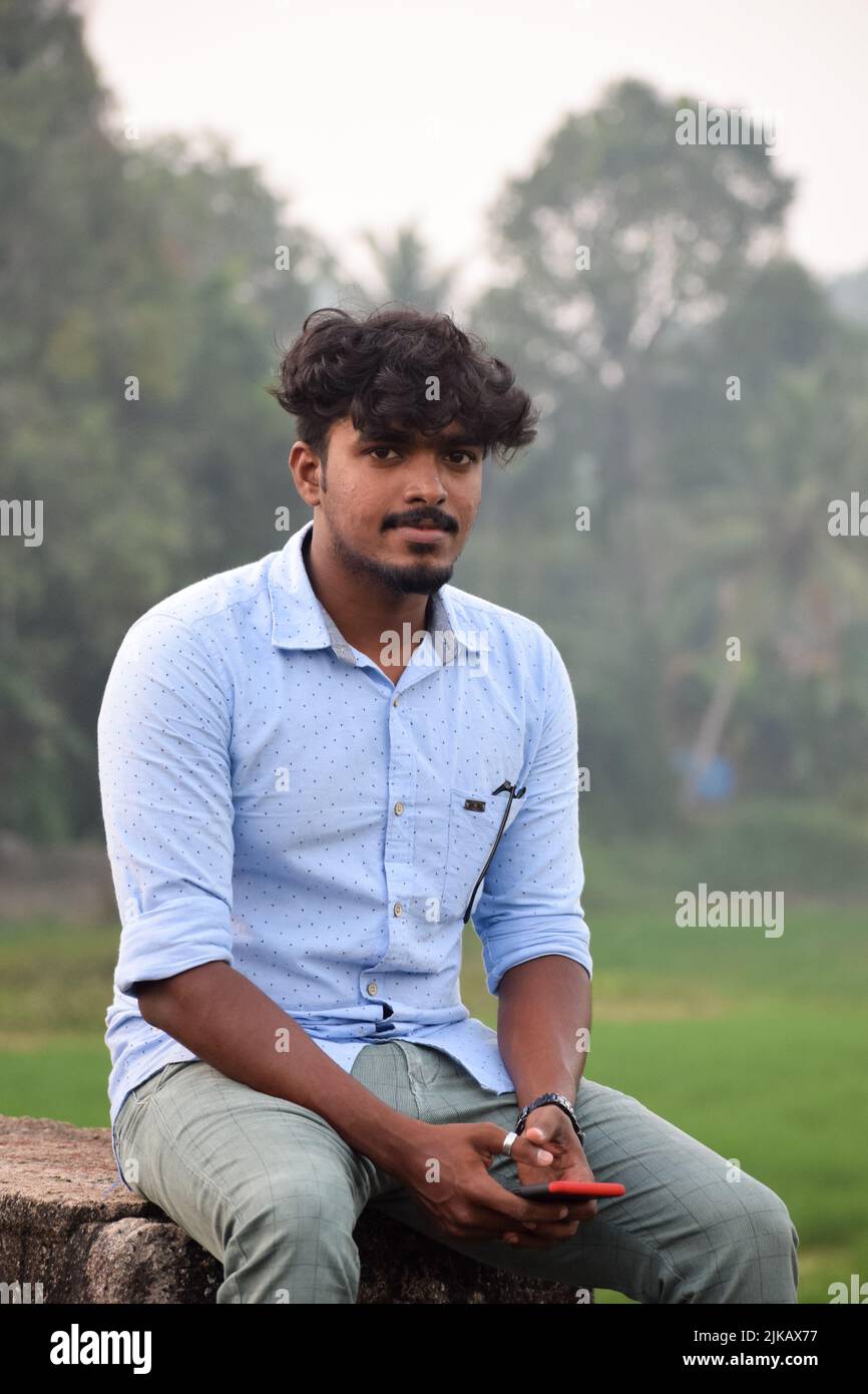 indian boy sitting on a cement bench and relaxing Stock Photo - Alamy