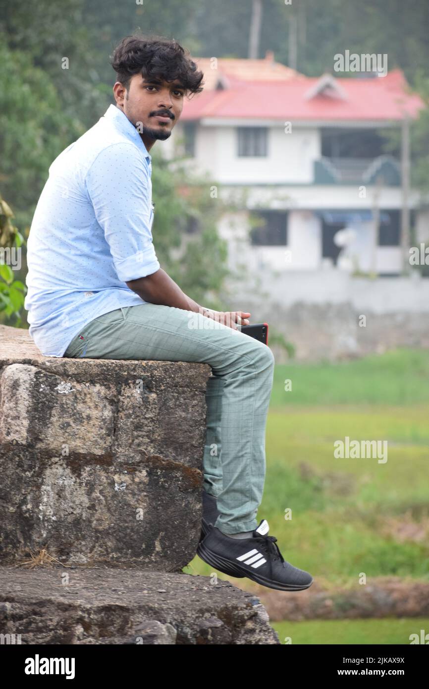 indian boy sitting on a cement bench and relaxing Stock Photo - Alamy