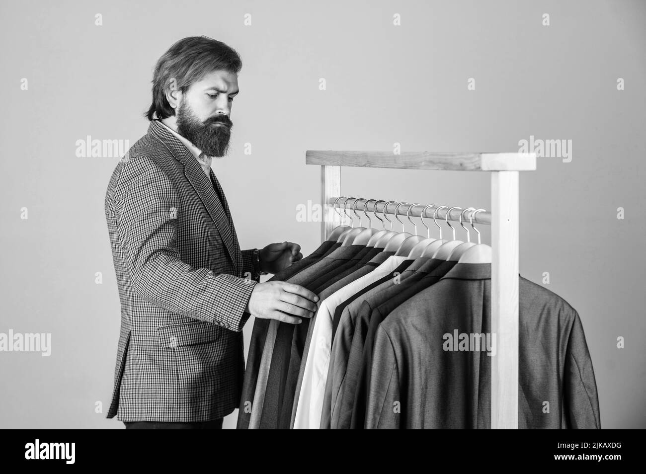 Businessman handsome guy in clothes shop choosing garments, demanding ...
