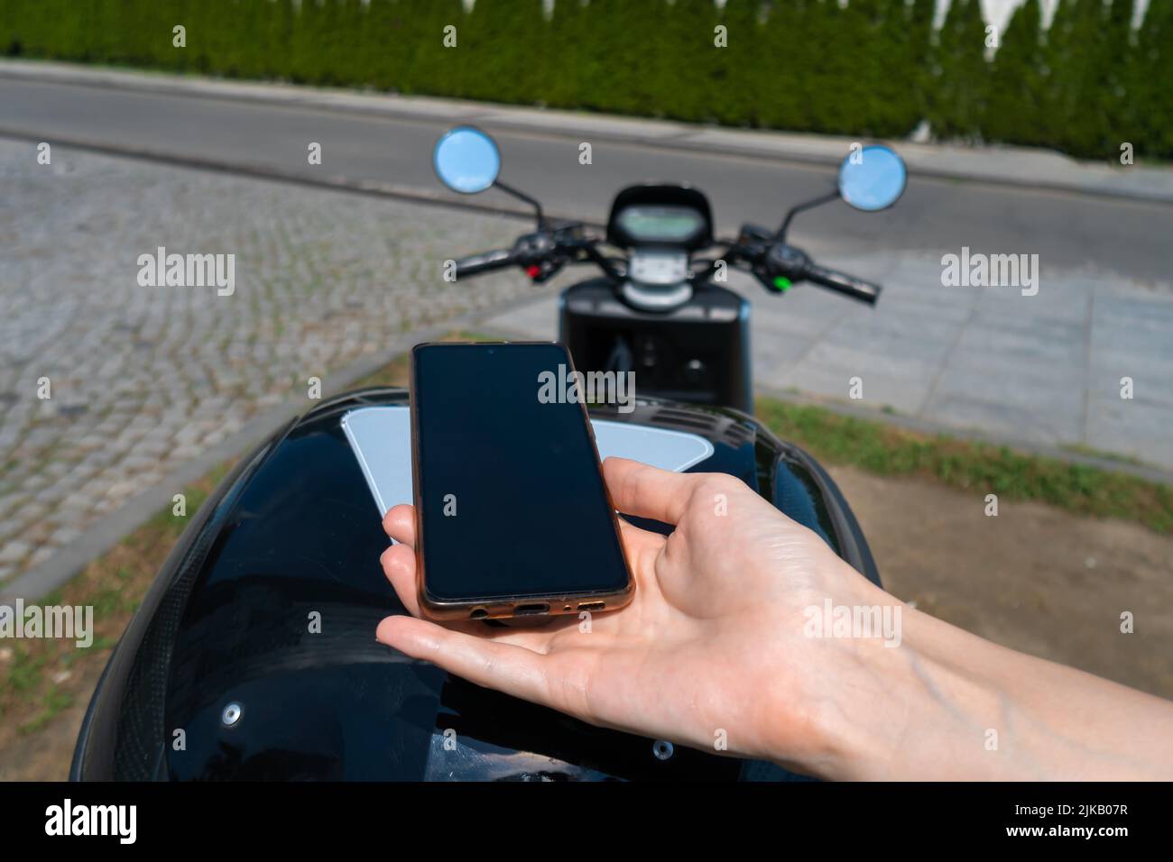 Woman's hand using a mobile phone scans the QR code on a motorcycle ...