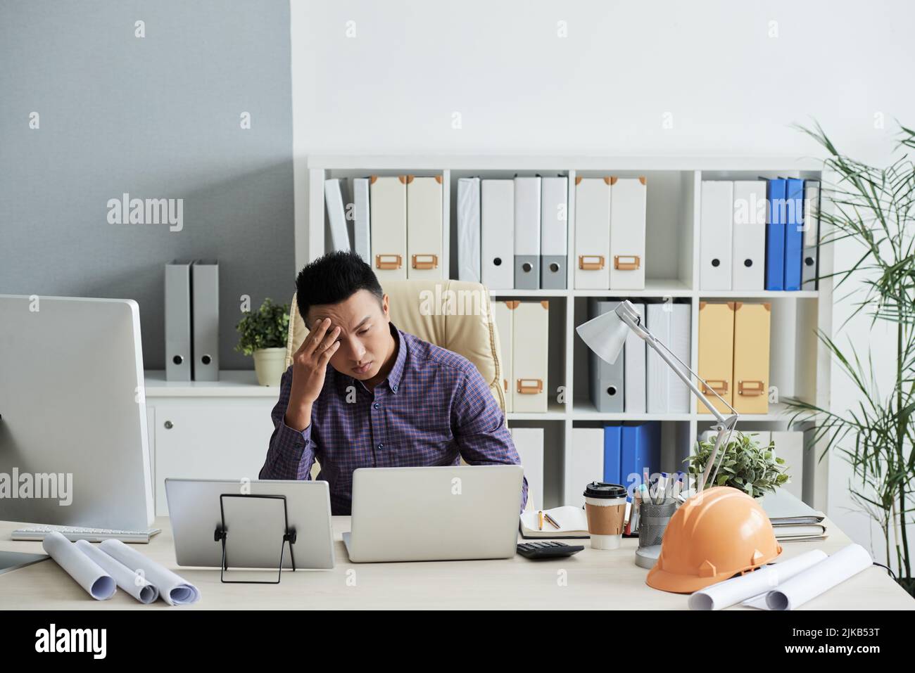 Very tired Asian engineer finishing work on his project Stock Photo - Alamy