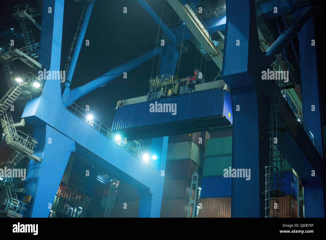 operation of container terminal at night. Unloading container ship at night. Mooring cranes ...