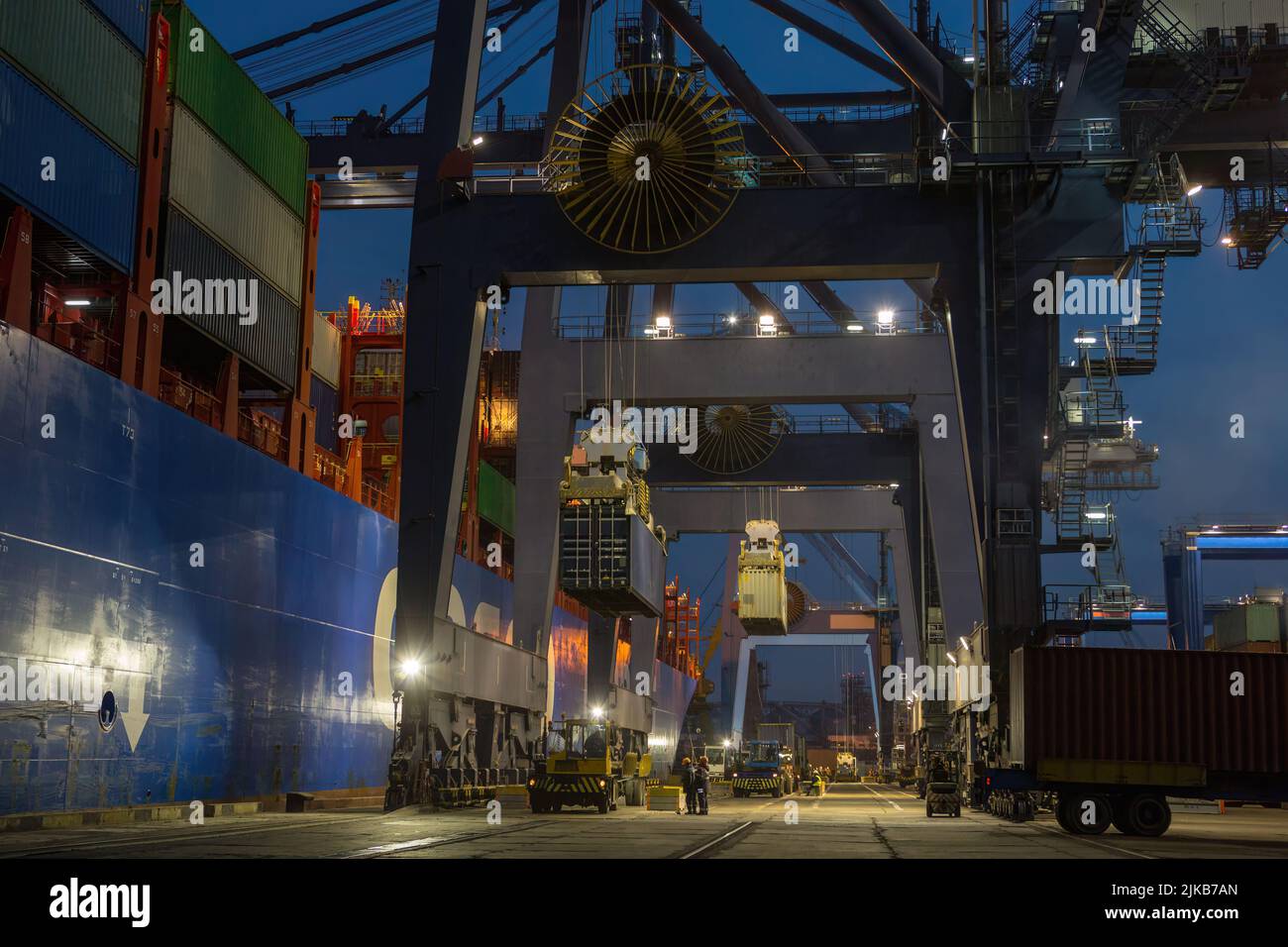 operation of container terminal at night. Unloading container ship at night. Mooring cranes ...